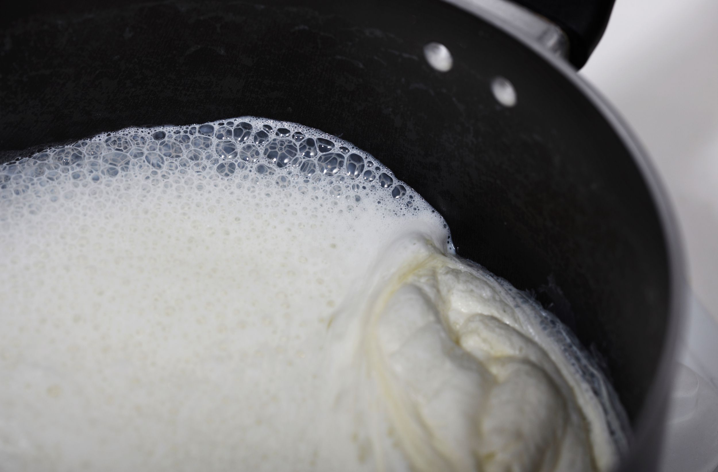 How do you keep milk from curdling when adding it to a hot liquid?