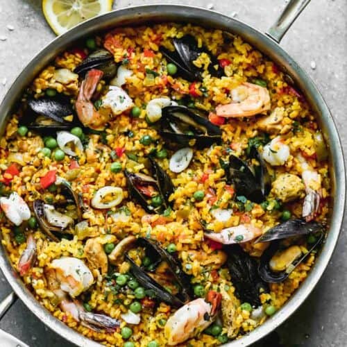 How is paella traditionally cooked?