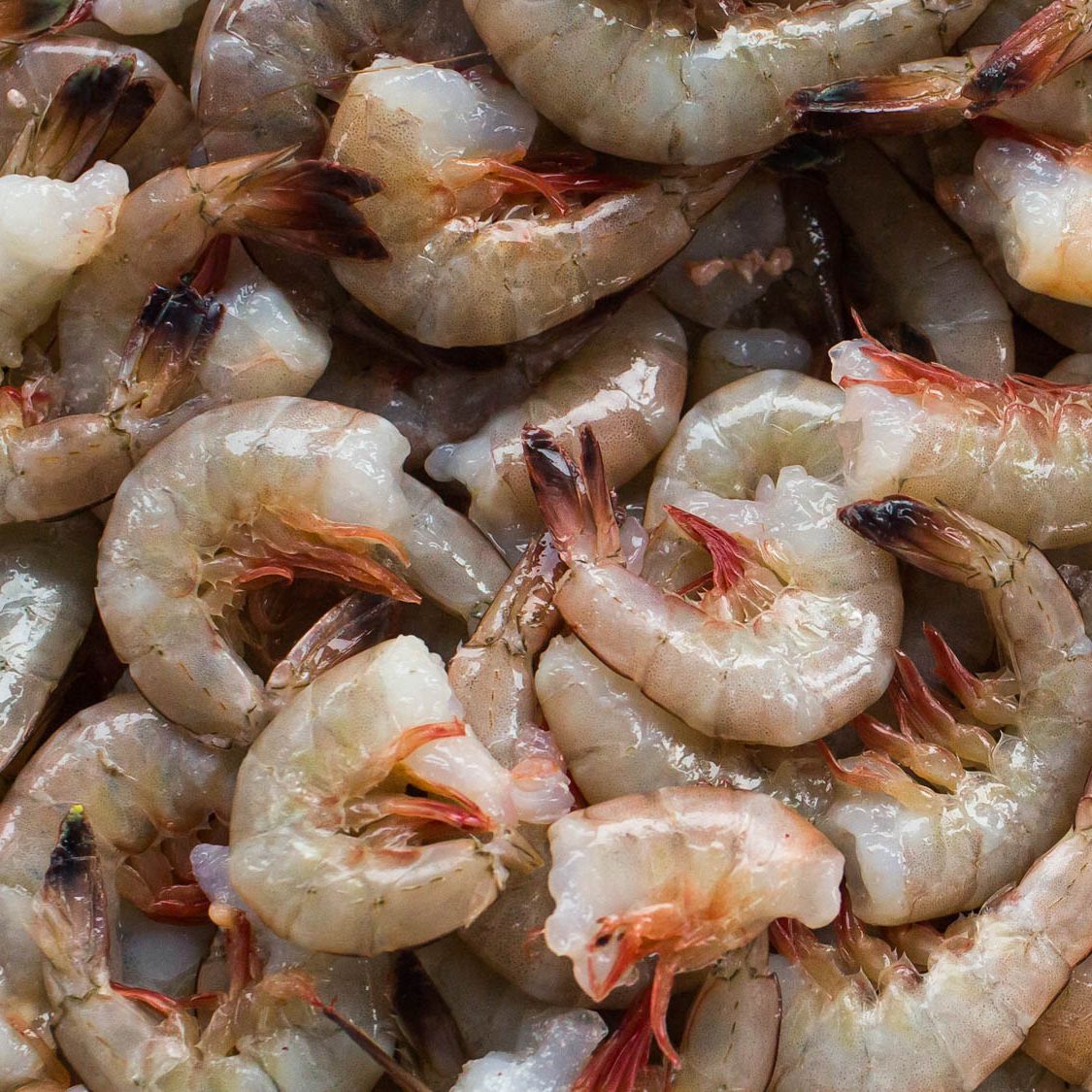 Is it better to buy cooked or raw frozen shrimp?