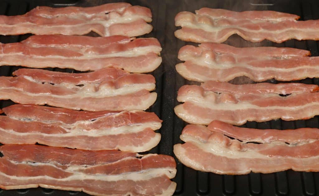 What happens if you eat bacon that isn't fully cooked?