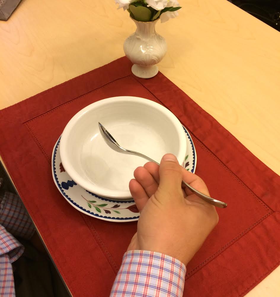 What is the proper way to eat soup with a spoon?